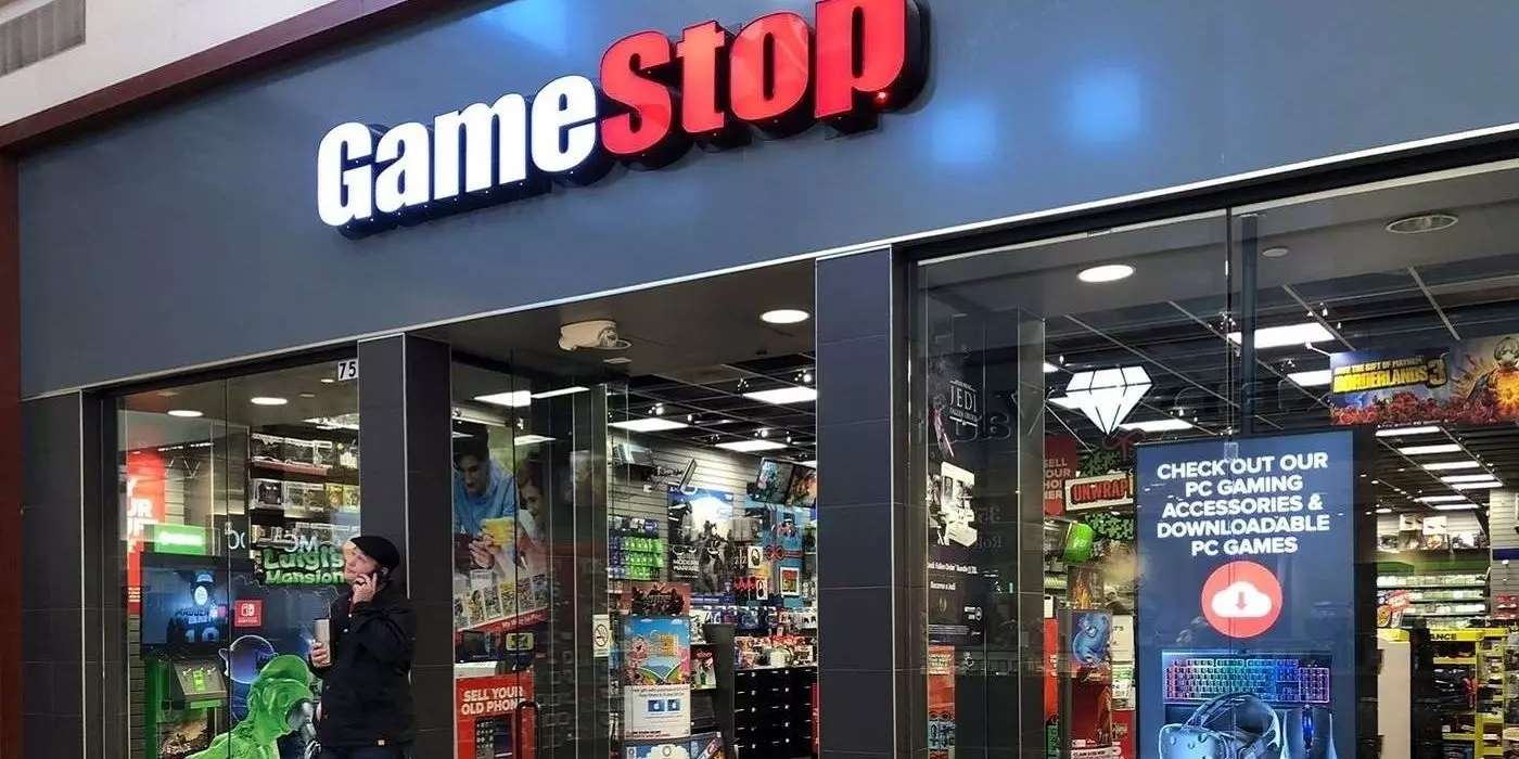 한 남자가 밖에 서서 휴대폰을 들고 있는 Gamestop 매장의 외부 사진