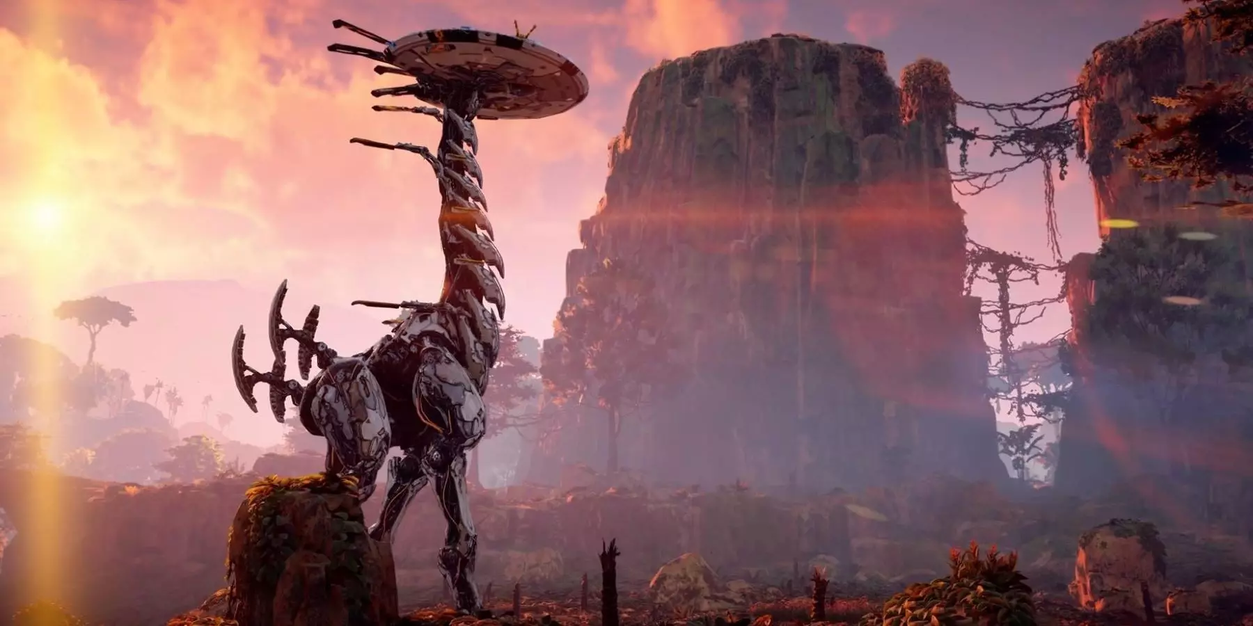 Vysoký krk z Horizon Zero Dawn procházející kolem zarostlé hory při západu slunce