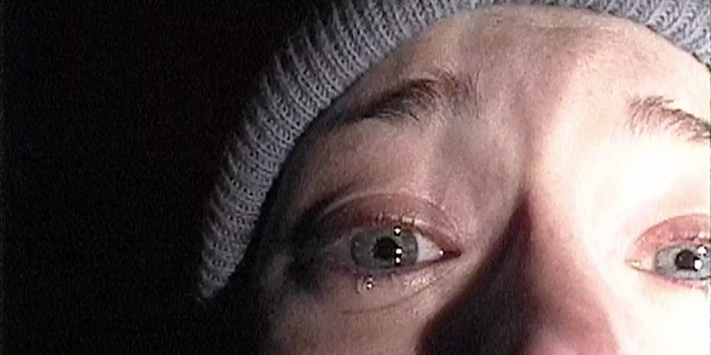 Heather zinema-ikasleak ikaratuta begiratzen dio bere kamerari The Blair Witch Project-eko beldurrezko filmak aurkitutako kartelean.