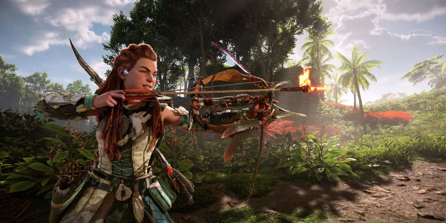 Aloy in einem grün-weißen Outfit mit einem kleinen, flachen Bogen, auf den ein Pfeil mit Flammenspitze klopfte