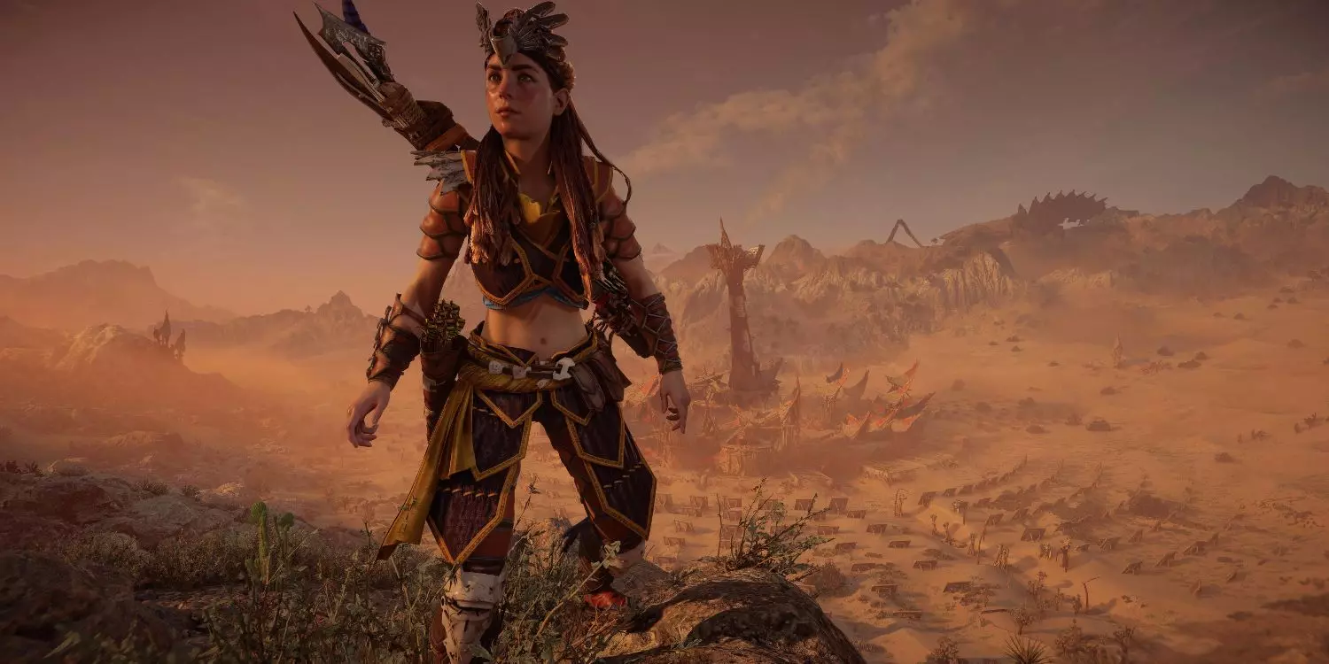 aloy debout sur une crête dans une tenue flashy avec une coiffe à plumes surplombant une ville avec une grande flèche au milieu