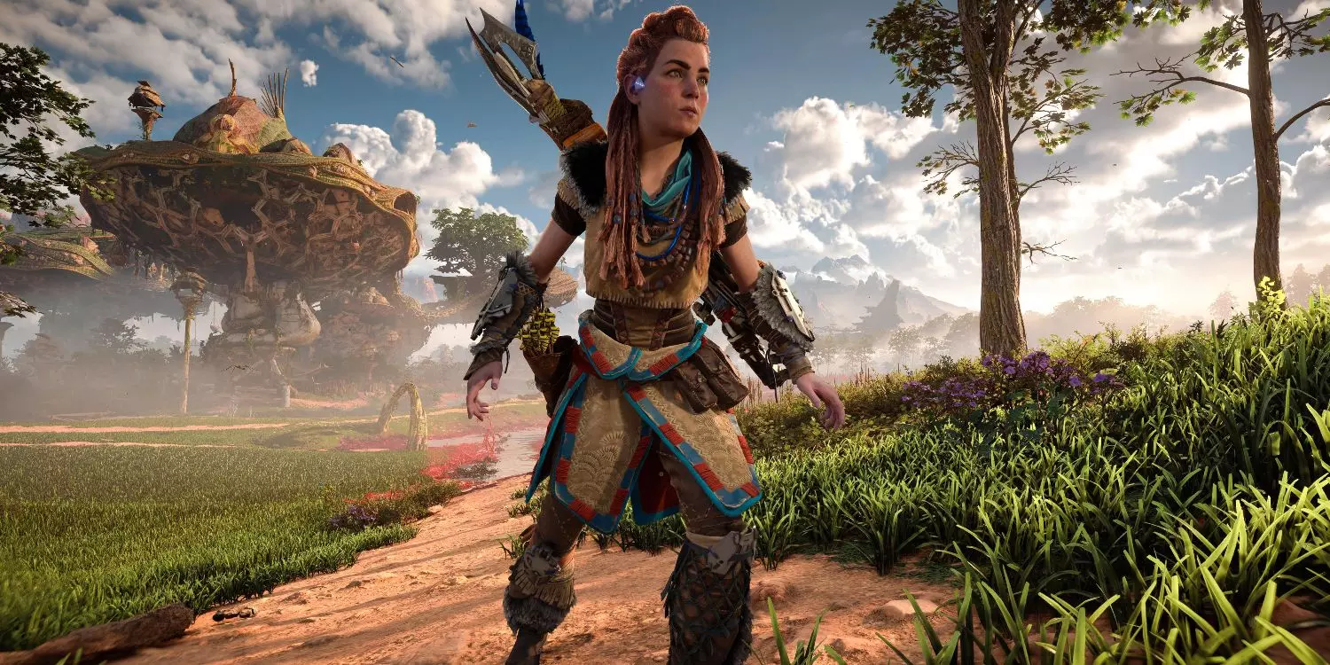 aloy dans une tenue beige en fourrure animale avec bordure bleue et rouge, debout dans un champ avec une grande structure en forme de champignon en arrière-plan